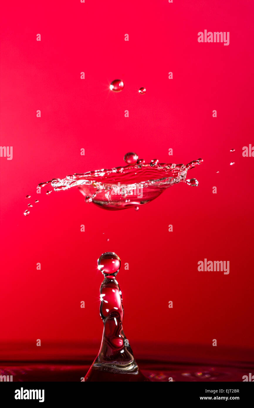 Water drop collisions with a red background Stock Photo - Alamy