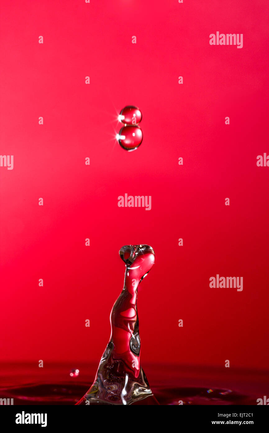 Water drop collisions with a red background Stock Photo - Alamy