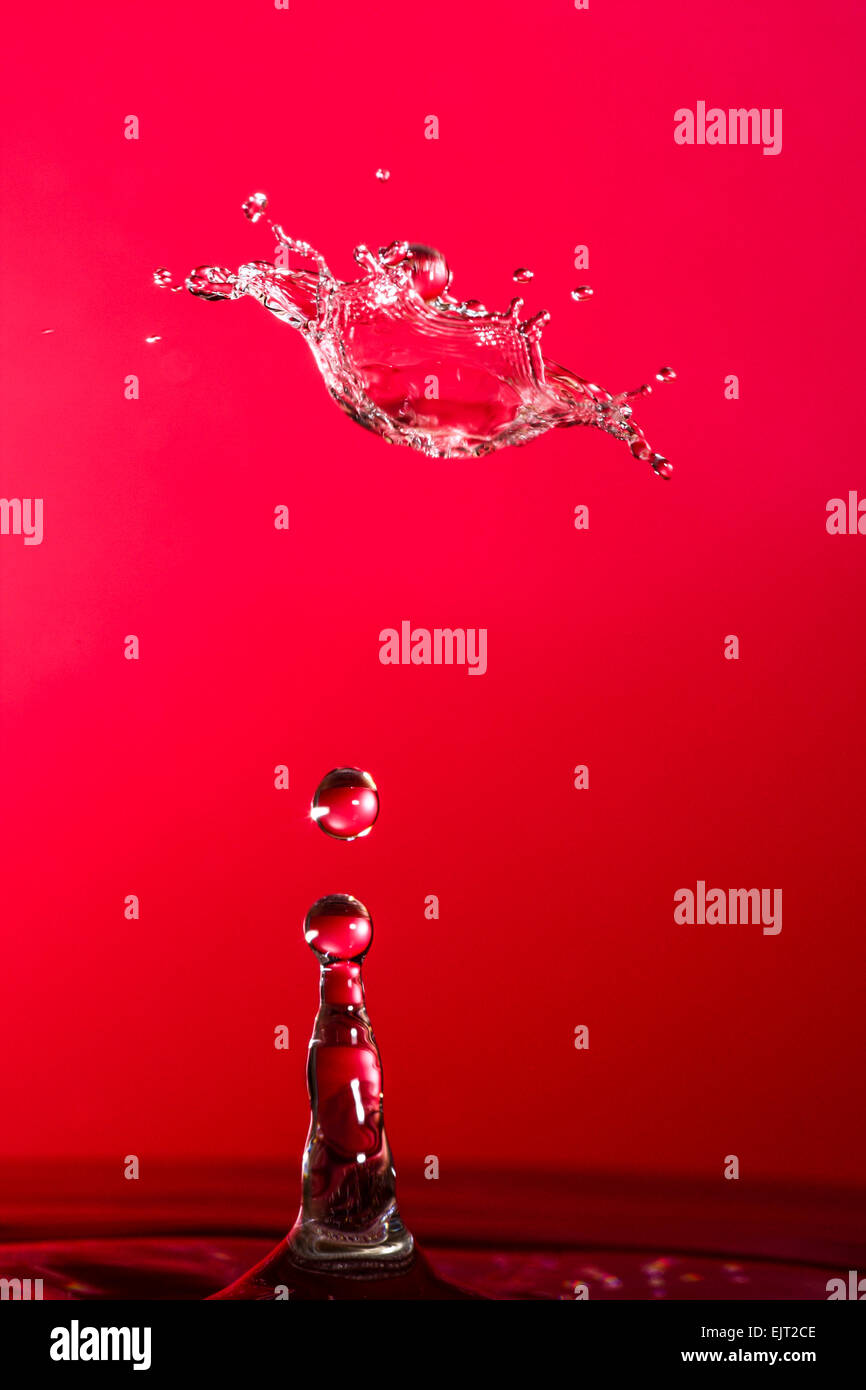 Water drop collisions with a red background Stock Photo - Alamy