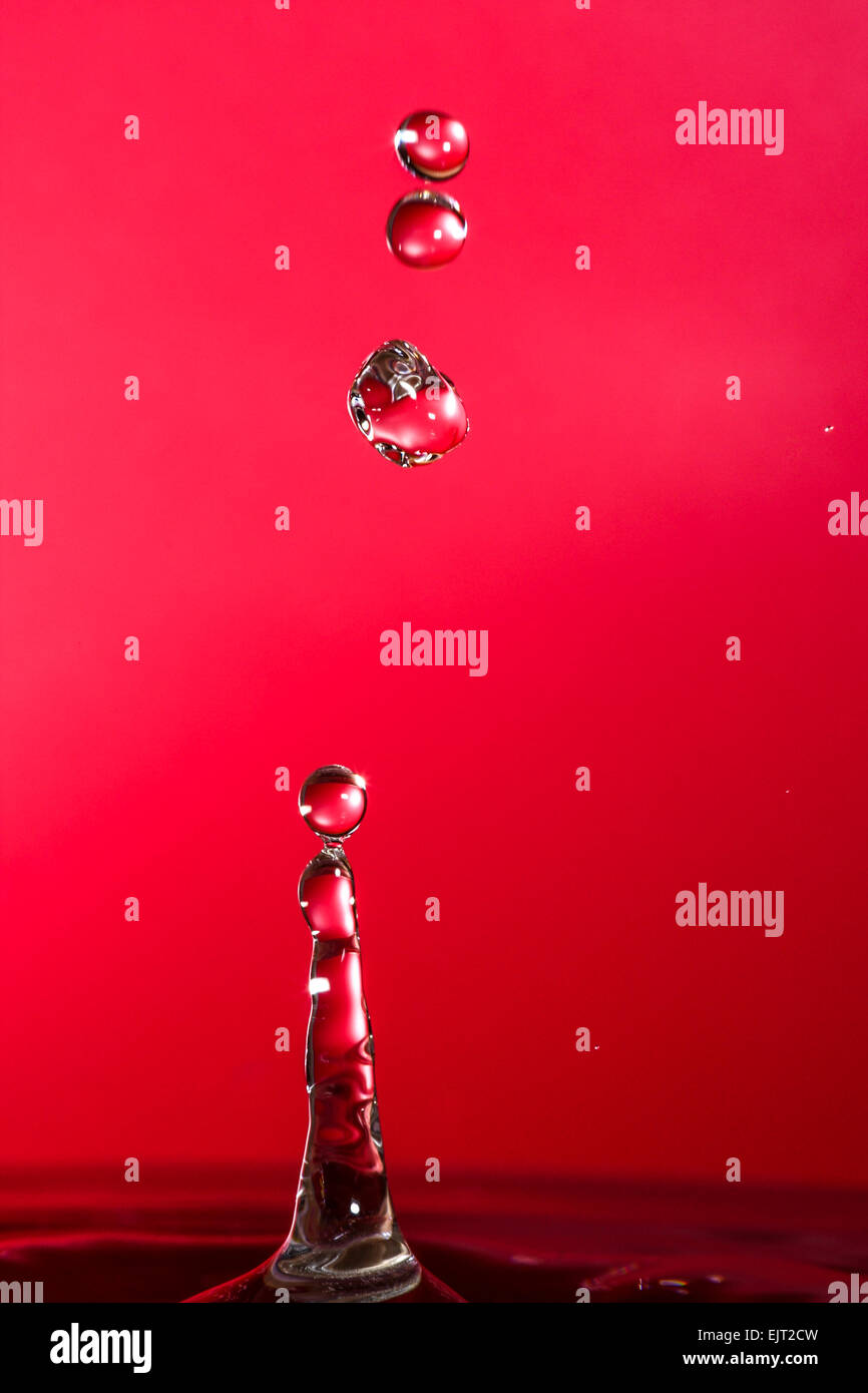 Water drop collisions with a red background Stock Photo - Alamy