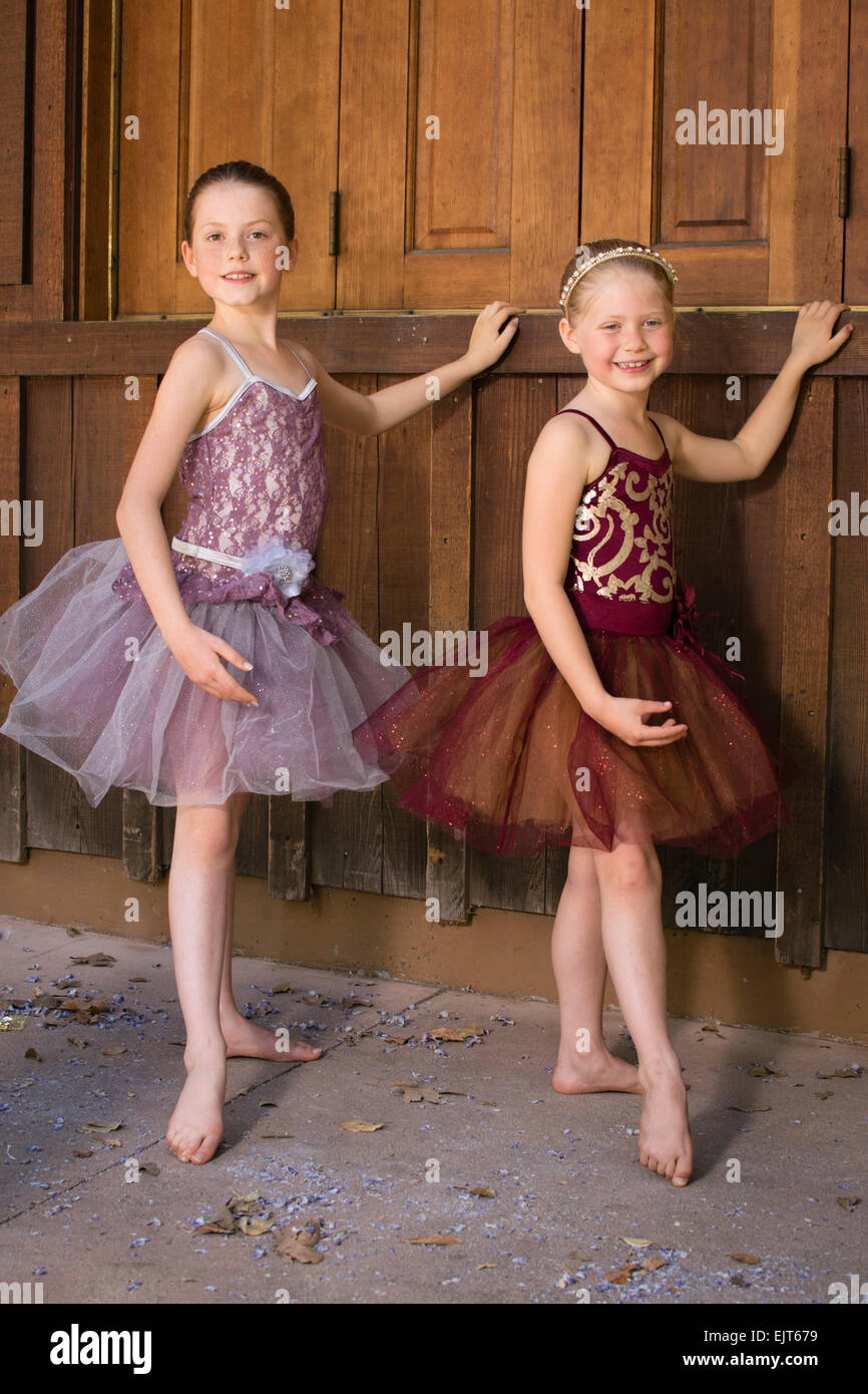 Two sisters in a ballet pose against a wood paneled wall Stock Photo ...