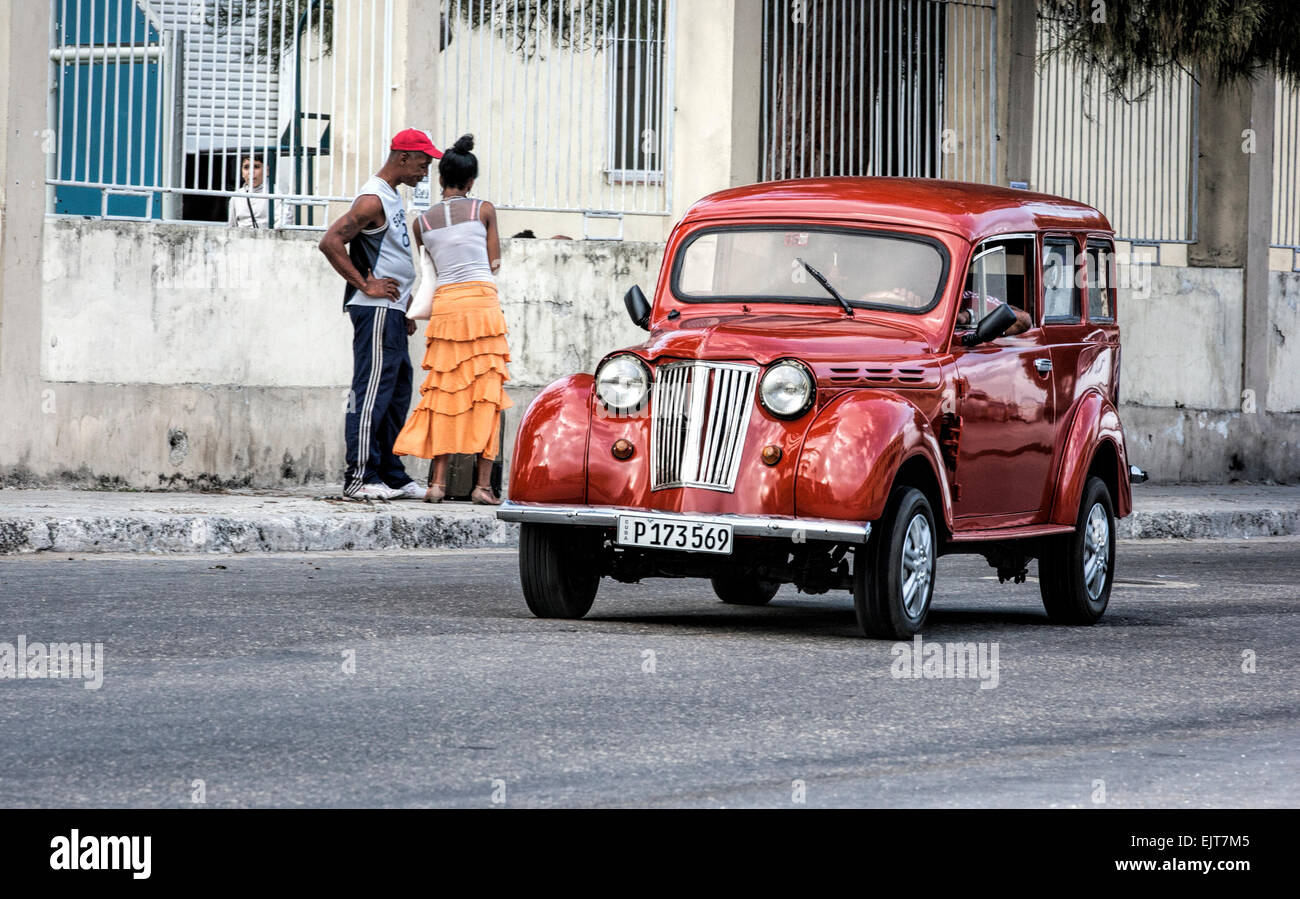 Old copper coloured American car in Cuba with brightly coloured Cubans ...