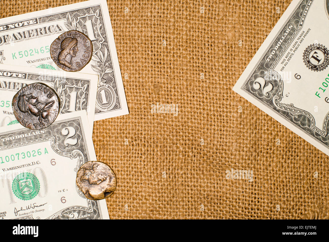Ancient coins with portraits of emperors and dollar notes on sacking ...