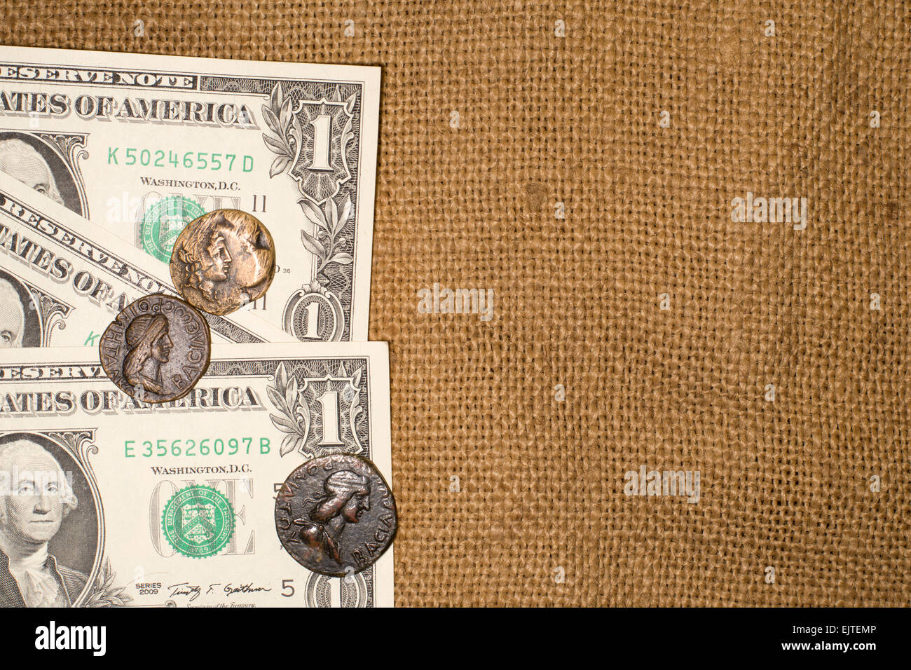 Ancient coins with portraits of emperors and dollar notes on sacking ...