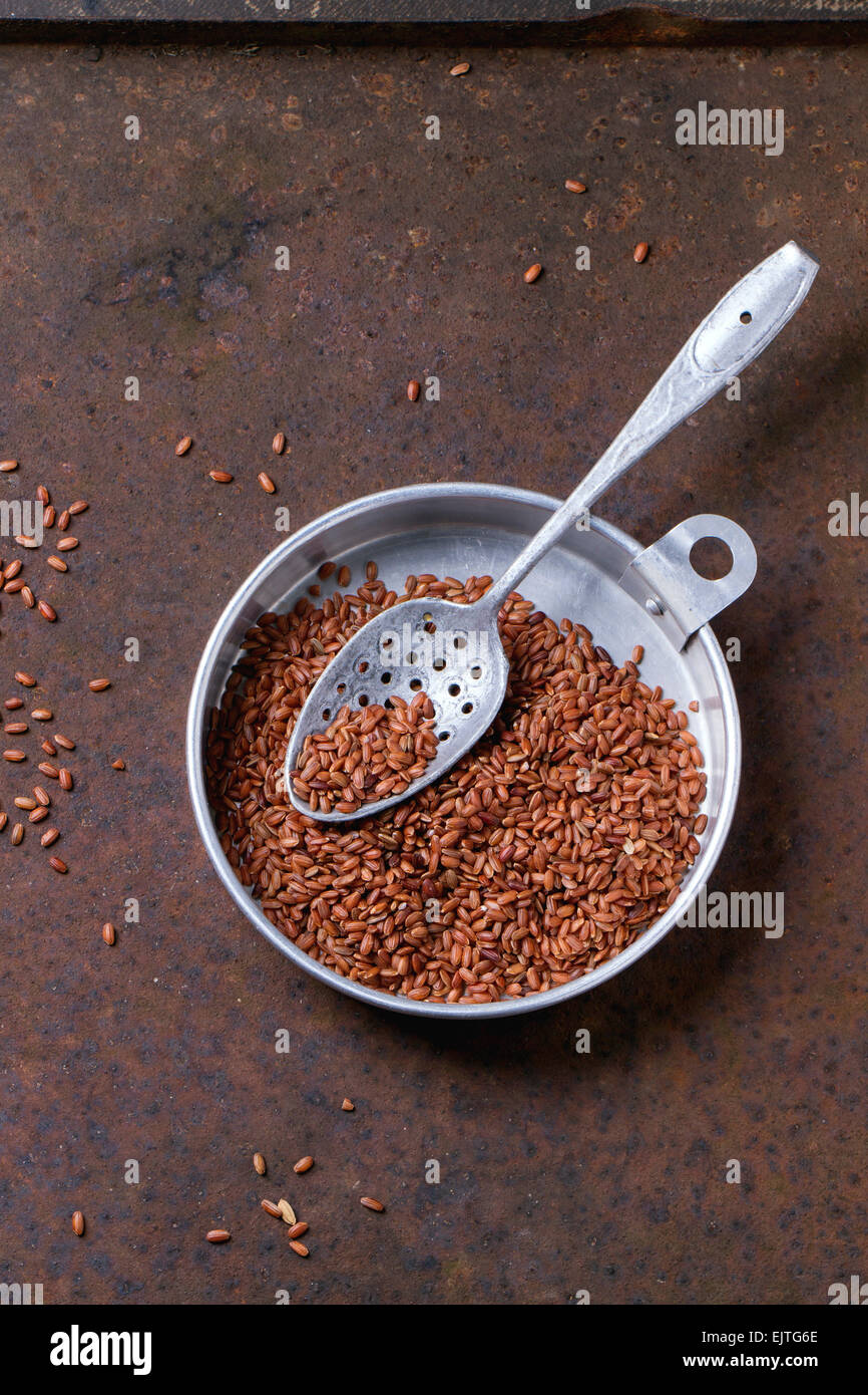 Uncooked brown rice on aluminium plate with aluminium spoon over brown ...