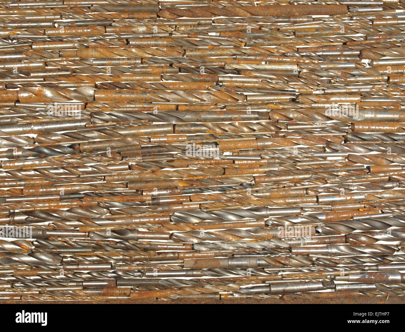 Background of old rusty drill bits of various sizes lying on a white ...