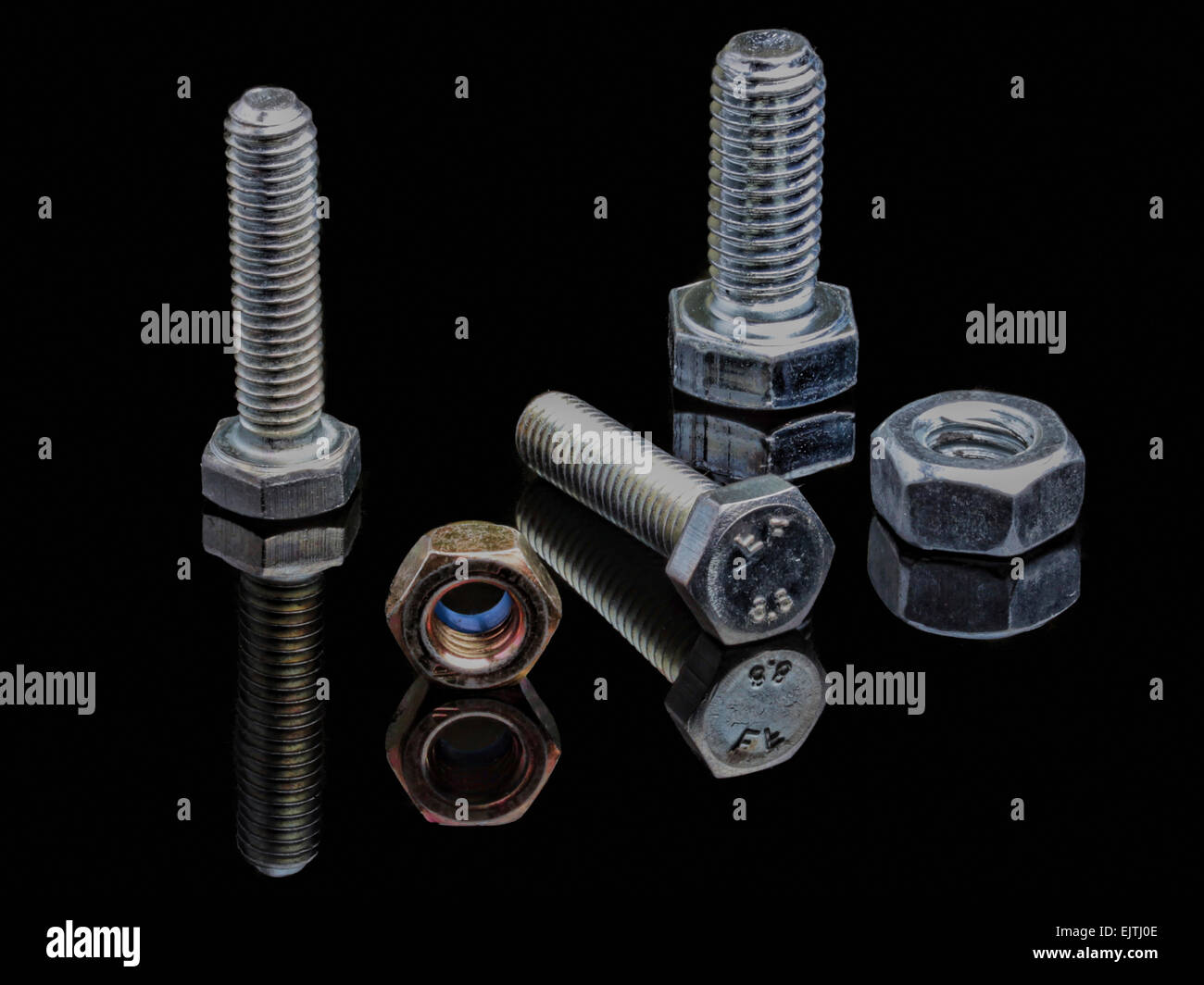 a variety of nuts and bolts on a black background with reflections on a ...