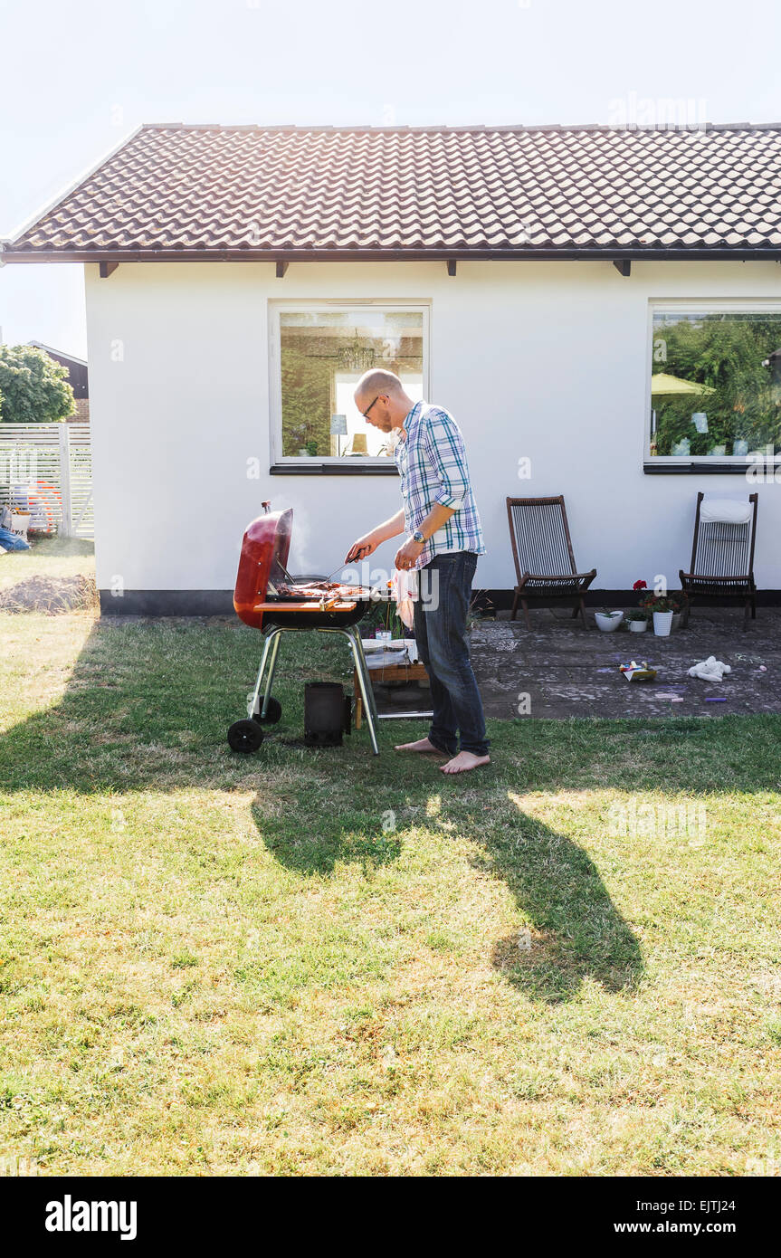 Full length of man grilling food outside house Stock Photo - Alamy