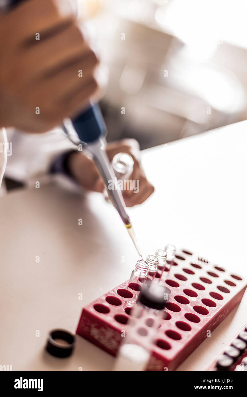 Researchers hand mixing solution from pipette in bottle at lab Stock ...