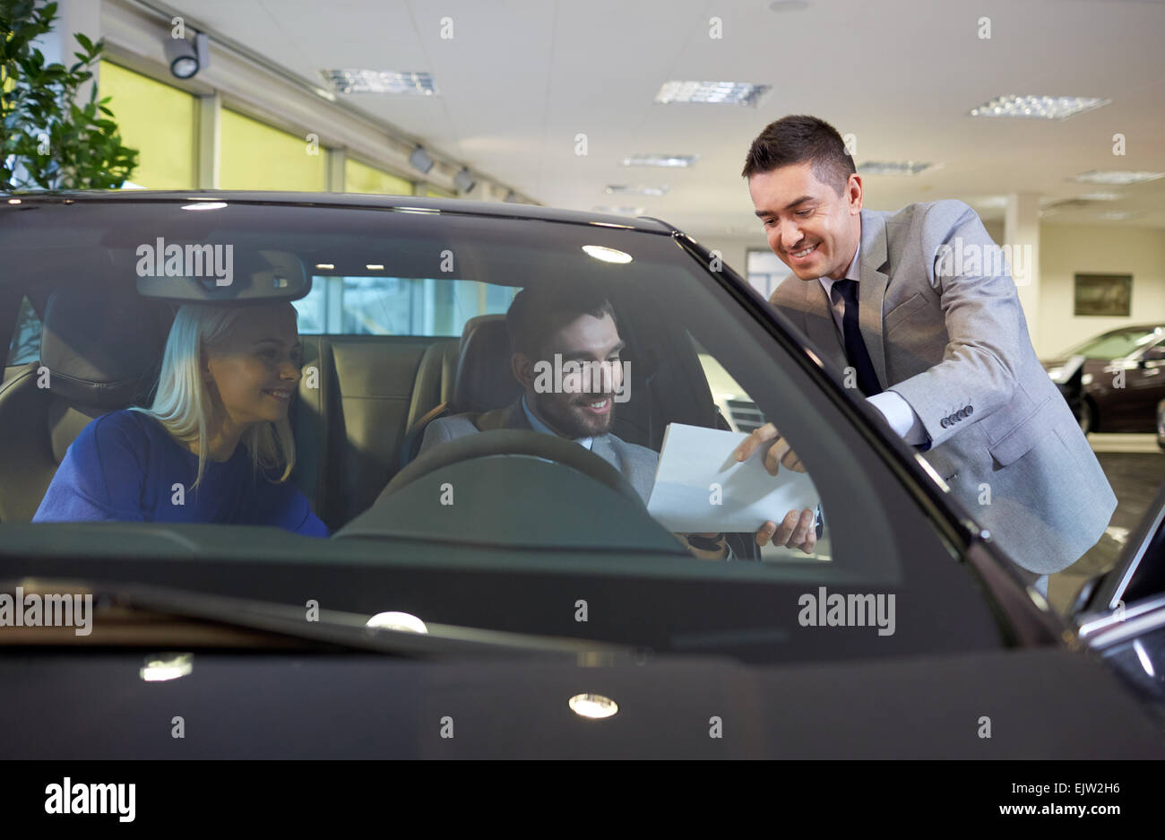 happy couple with car dealer in auto show or salon Stock Photo - Alamy