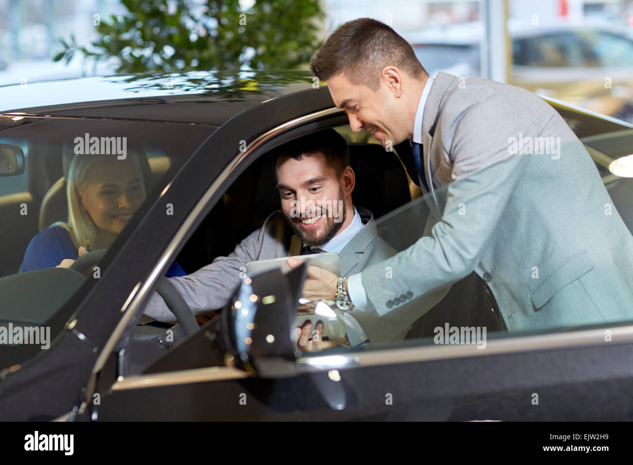 happy couple with car dealer in auto show or salon Stock Photo - Alamy