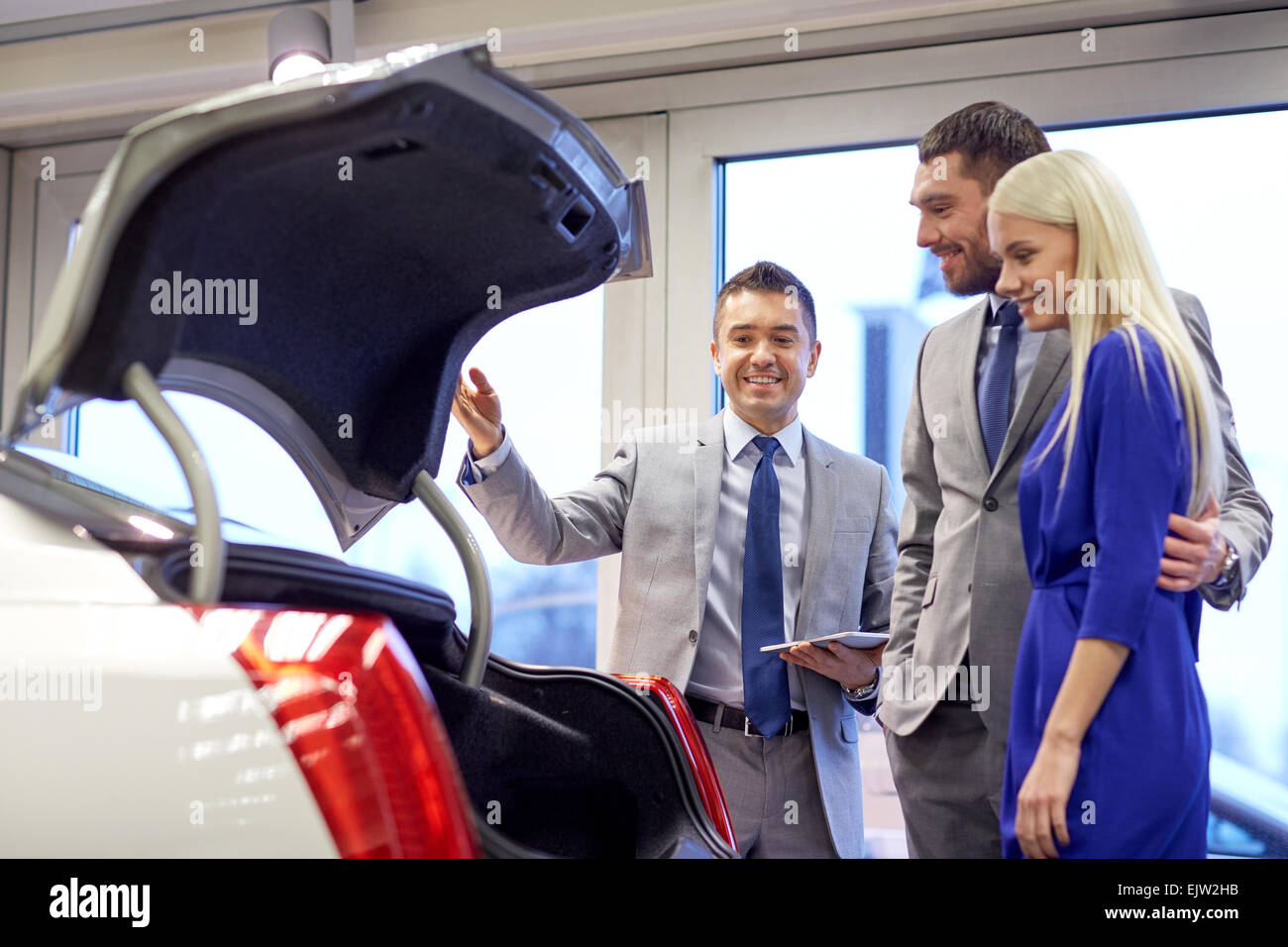 happy couple with car dealer in auto show or salon Stock Photo - Alamy