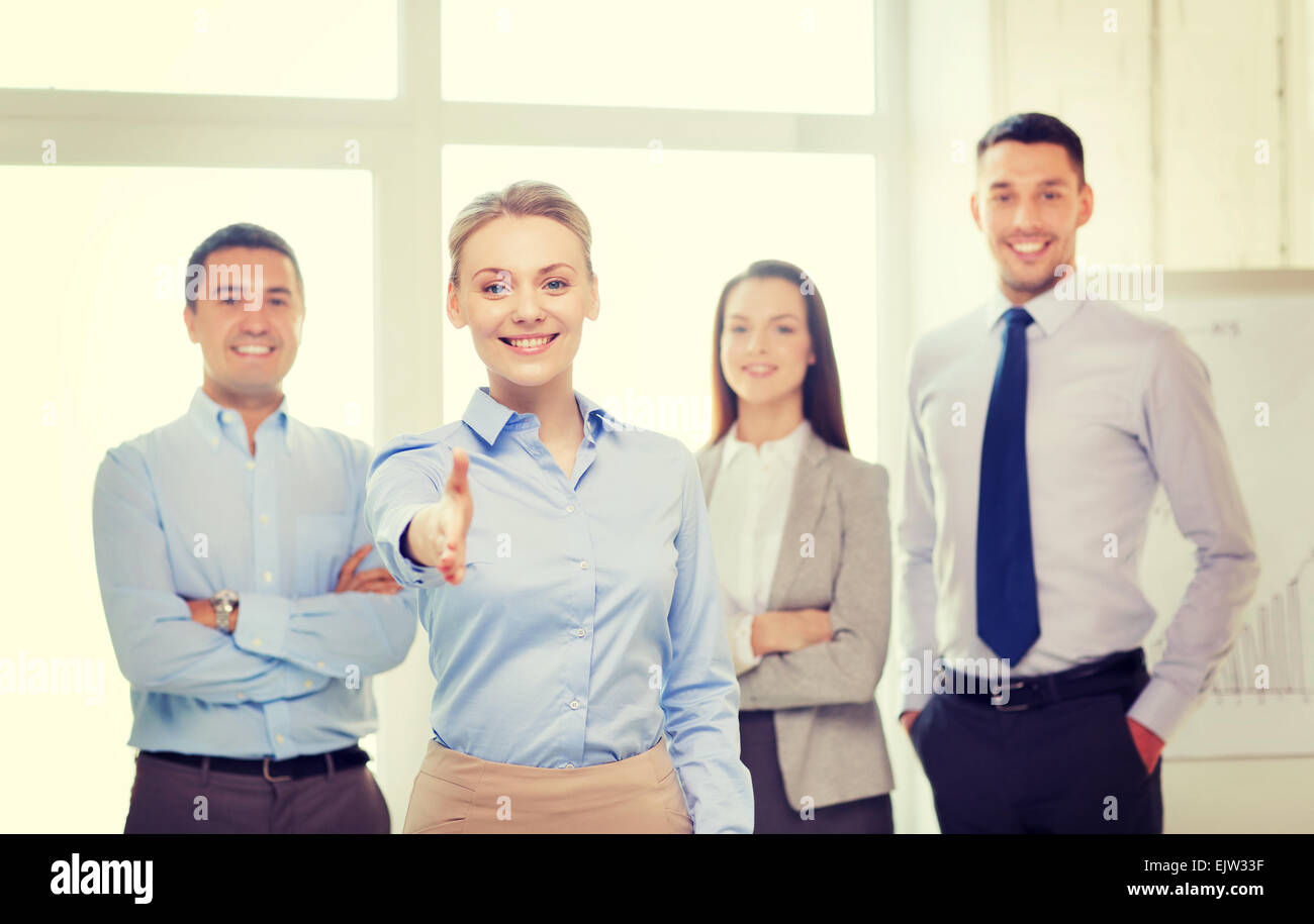 smiling businesswoman in office with team on back Stock Photo - Alamy