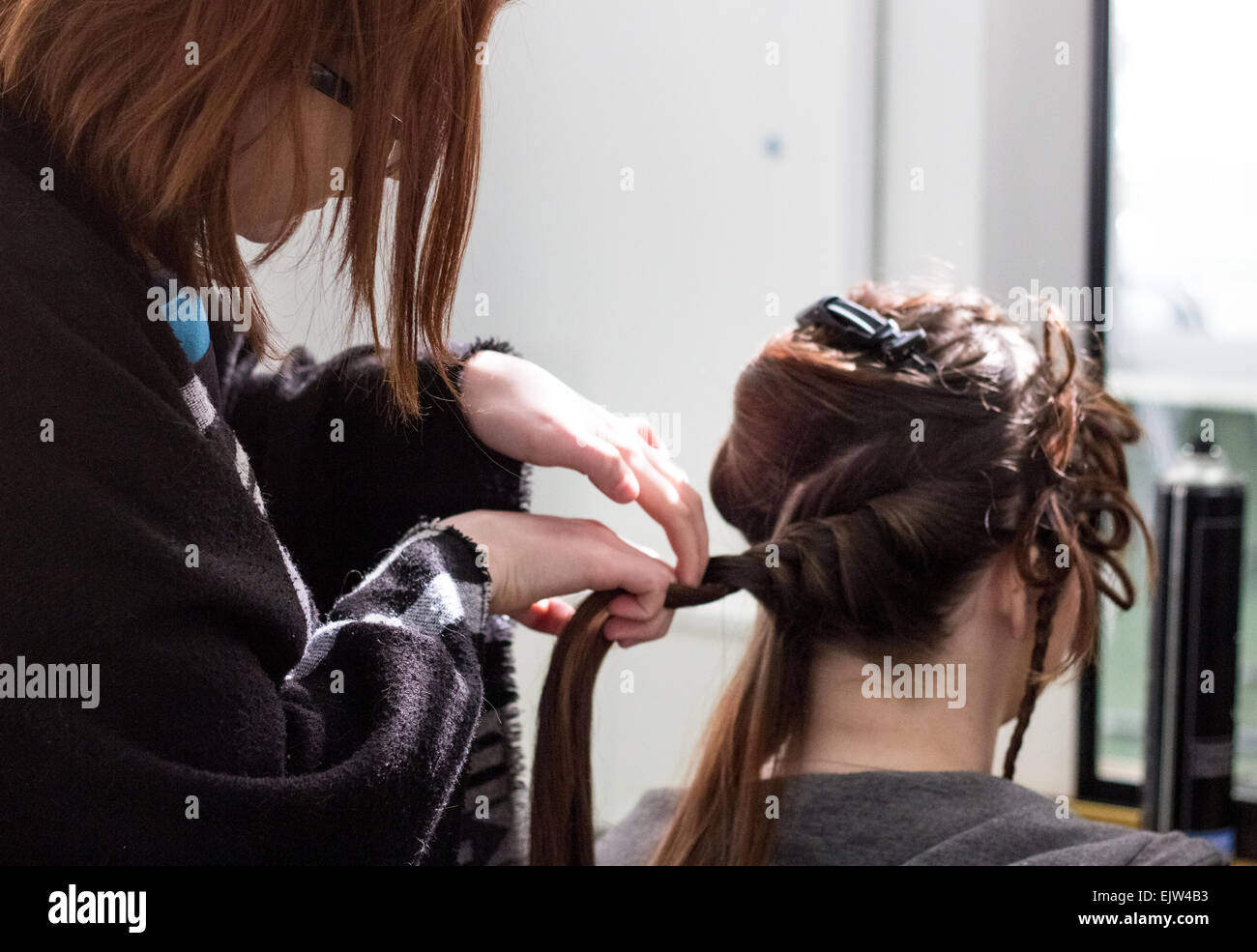 Female hairdresser twisting and braiding a female models hair ready for ...