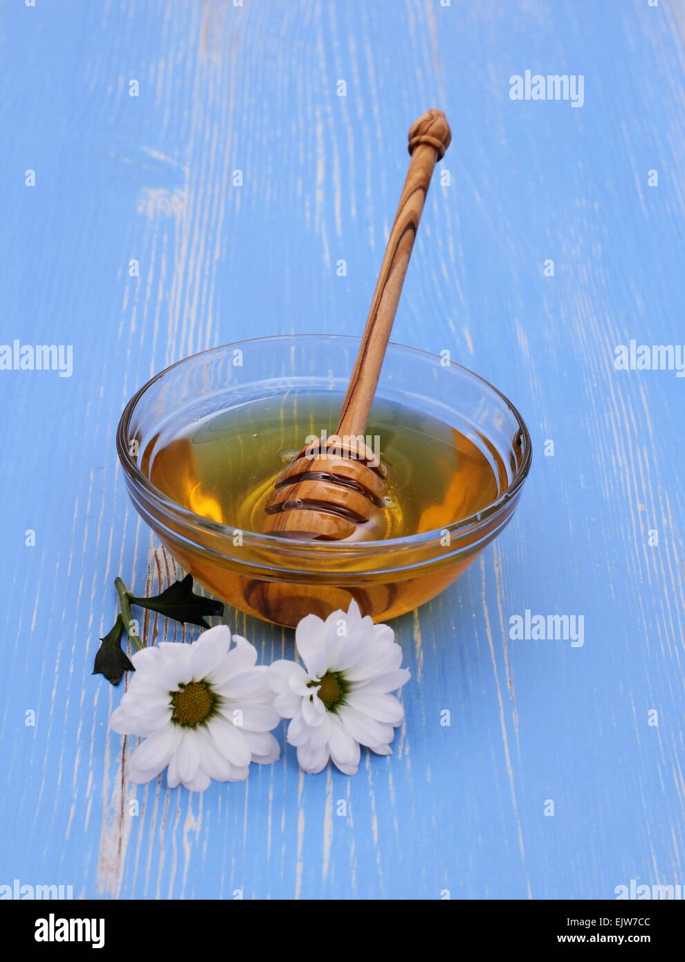 Honey bowl with dipper and blossom on blue wood table Stock Photo - Alamy