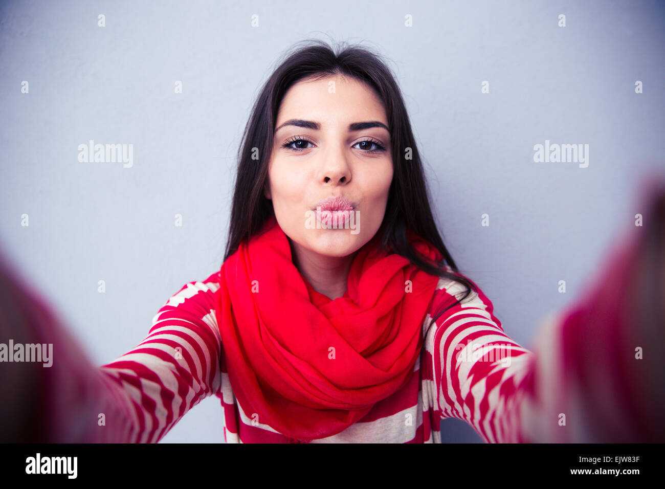 Beautiful woman kissing at camera over gray background. Wearing in pink ...