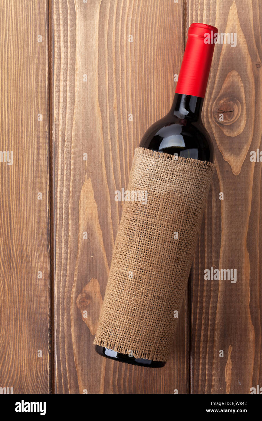Red wine bottle over rustic wooden table background Stock Photo - Alamy