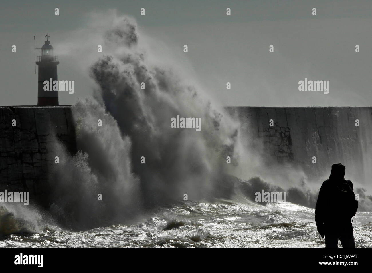 A man watches as waves crash against the harbour wall at Newhaven in ...