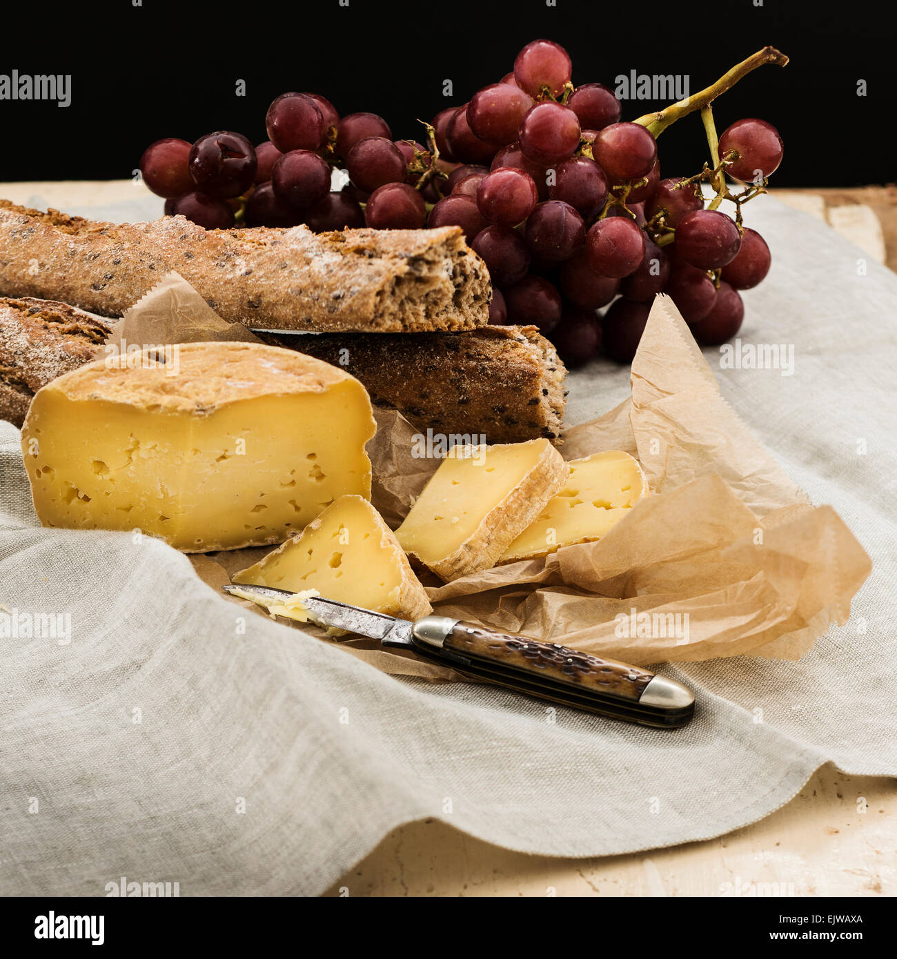 Still life with grapes and cheese and bread slices on wooden table ...
