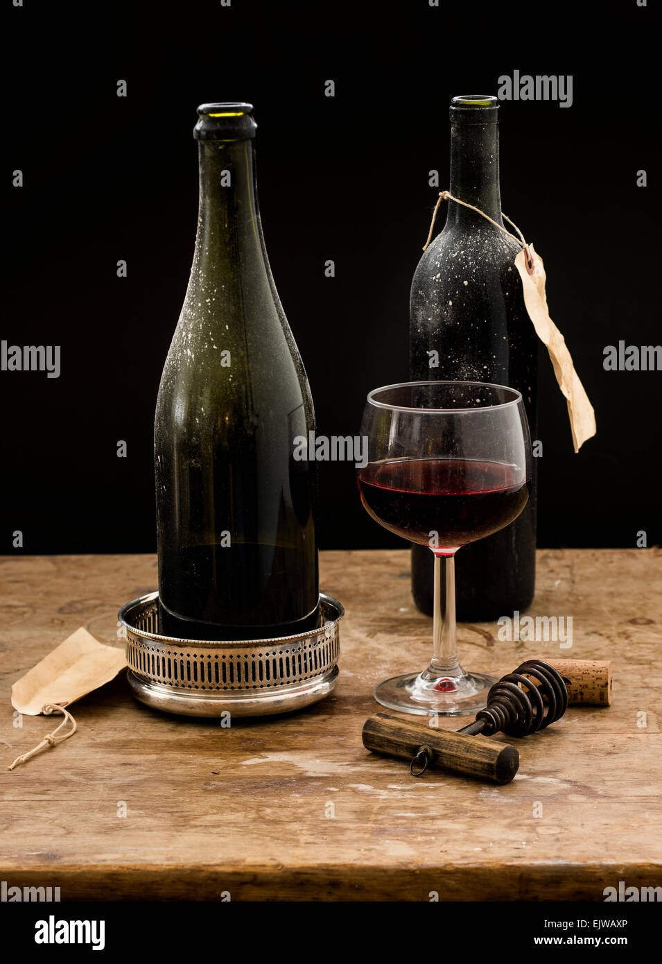 Still life with red wine glass and bottles on wooden table, studio shot ...