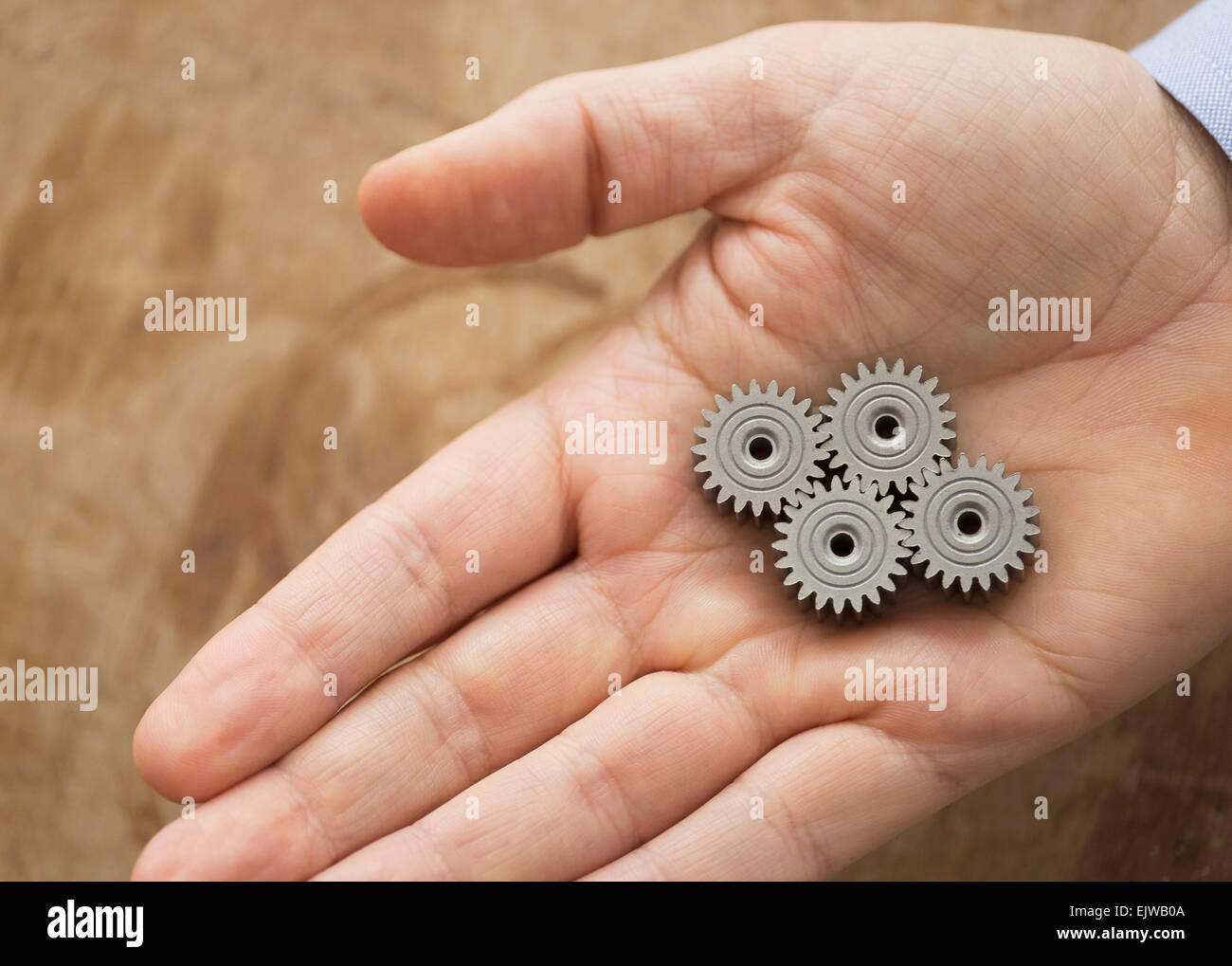 Close up of man's hand holding metal cogs Stock Photo - Alamy