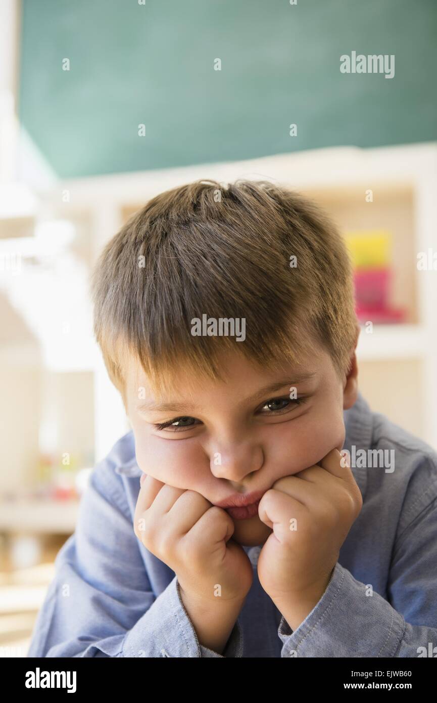 Portrait of frustrated boy (6-7) sitting in classroom Stock Photo - Alamy