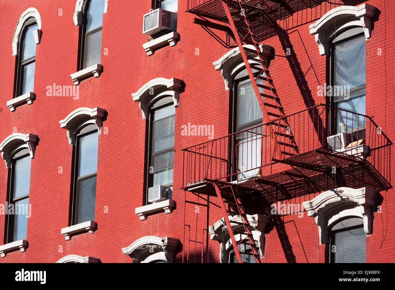 USA, New York, New York City, Facade of red building with fire escape ...