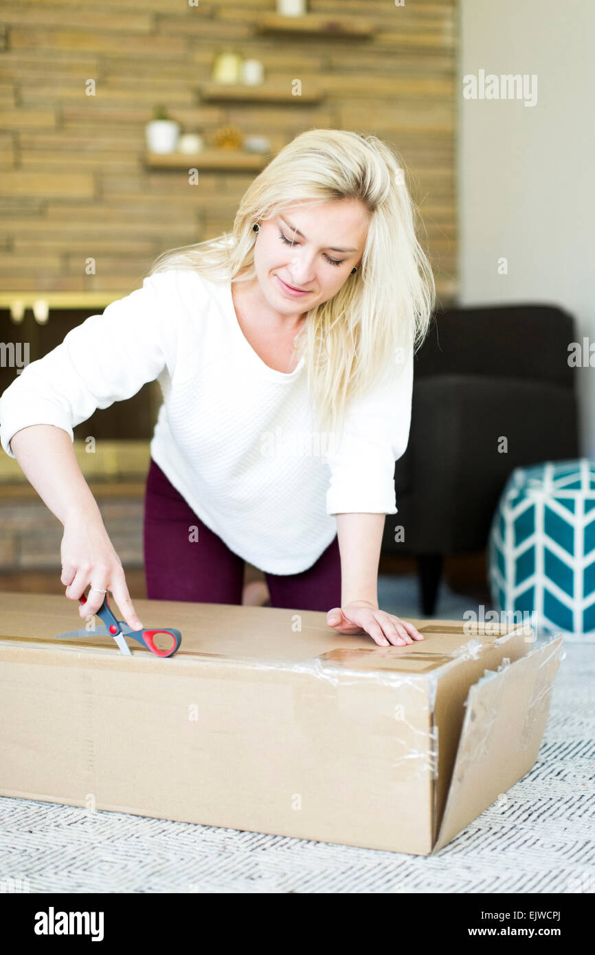 Young woman opening box with scissors Stock Photo - Alamy
