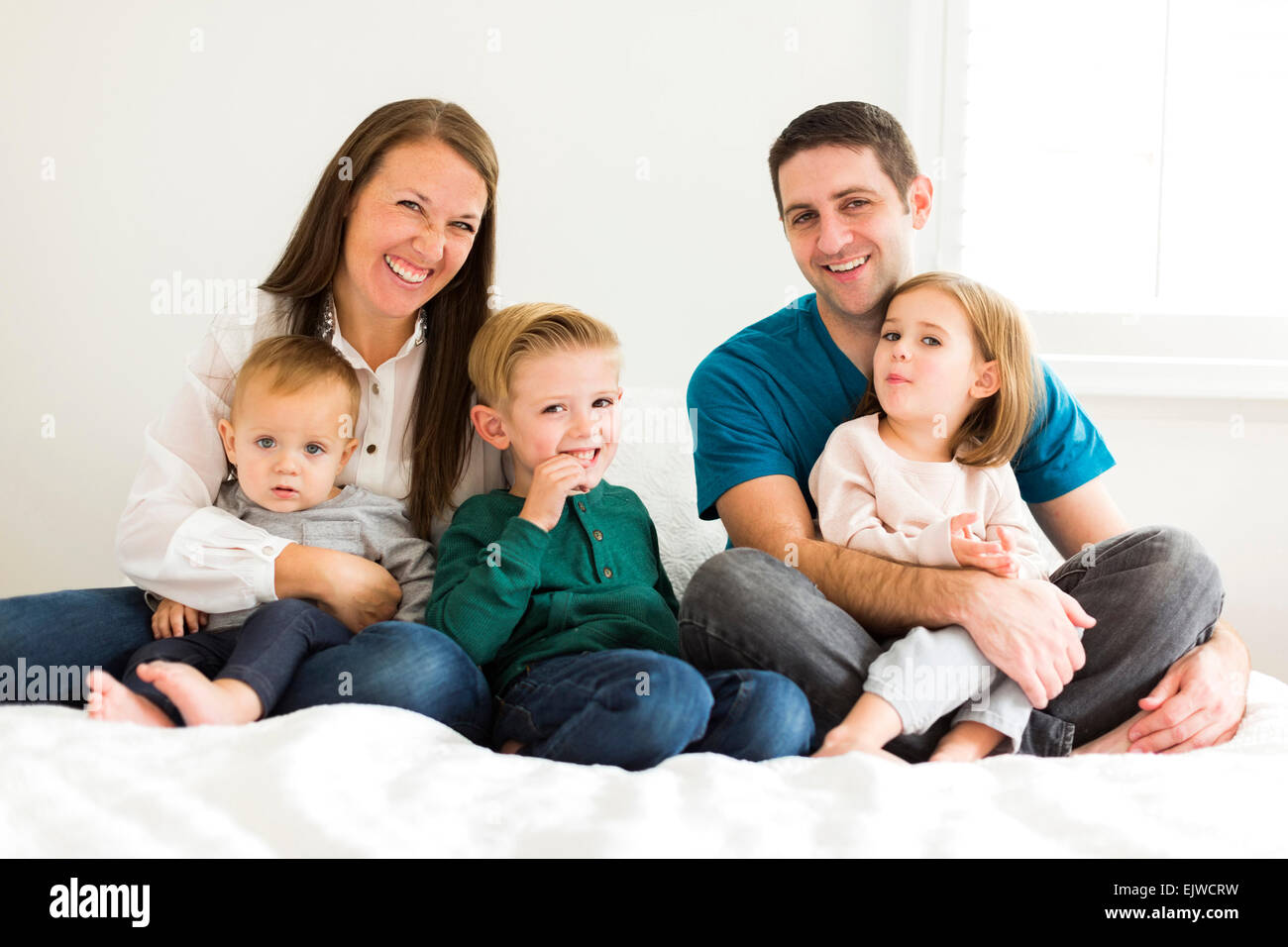 Portrait of family with three children (2-3, 4-5) sitting on bed Stock ...