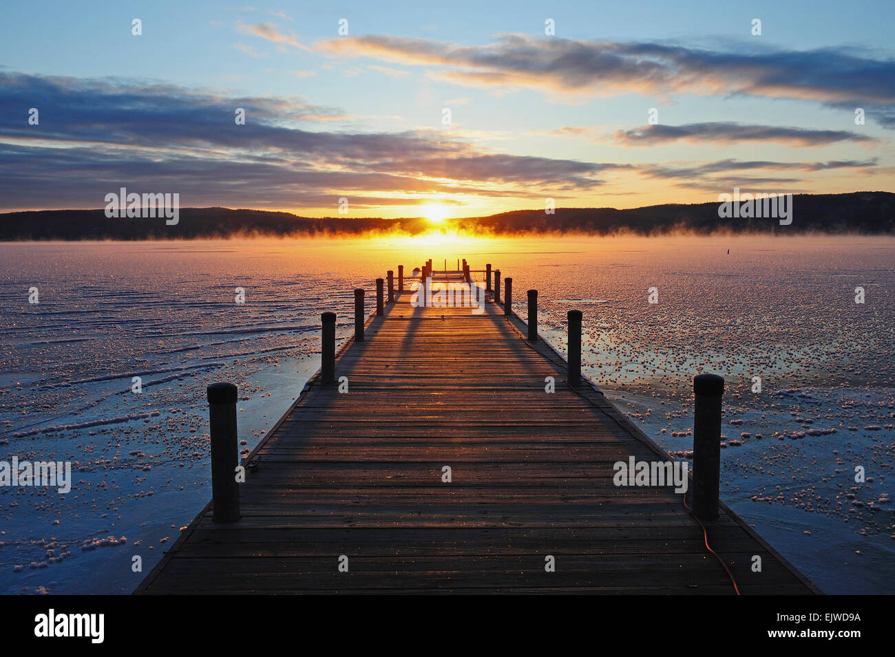 USA, New York, Lake George, Symmetrical view of jetty on frozen lake ...