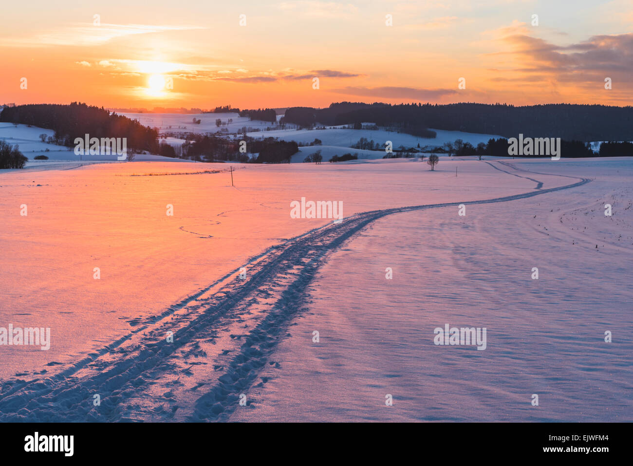Scene with trail on snow at sunset background Stock Photo - Alamy