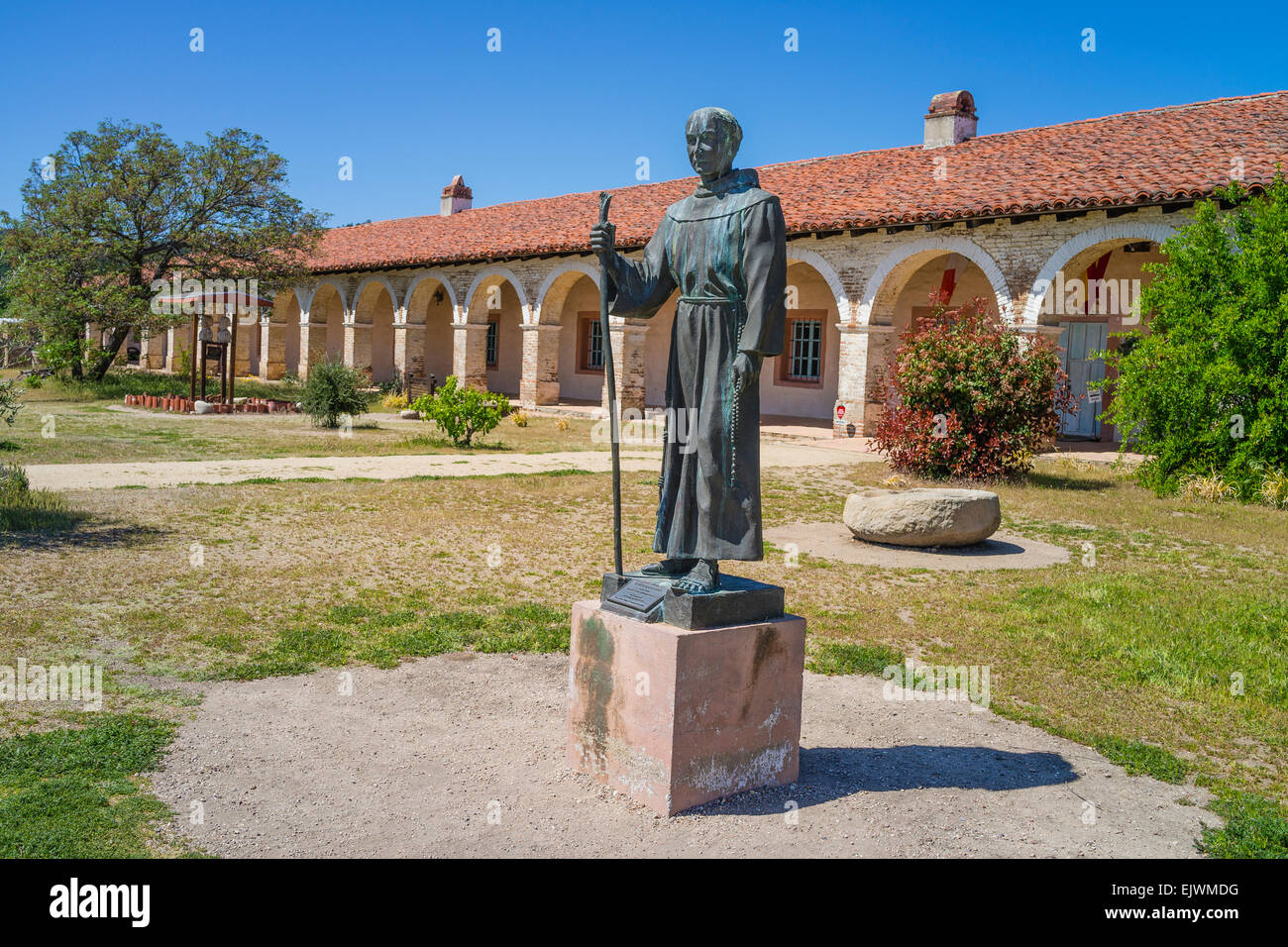 Bronze statue of Fr. Junipero Serra in front of the red tile roof and ...