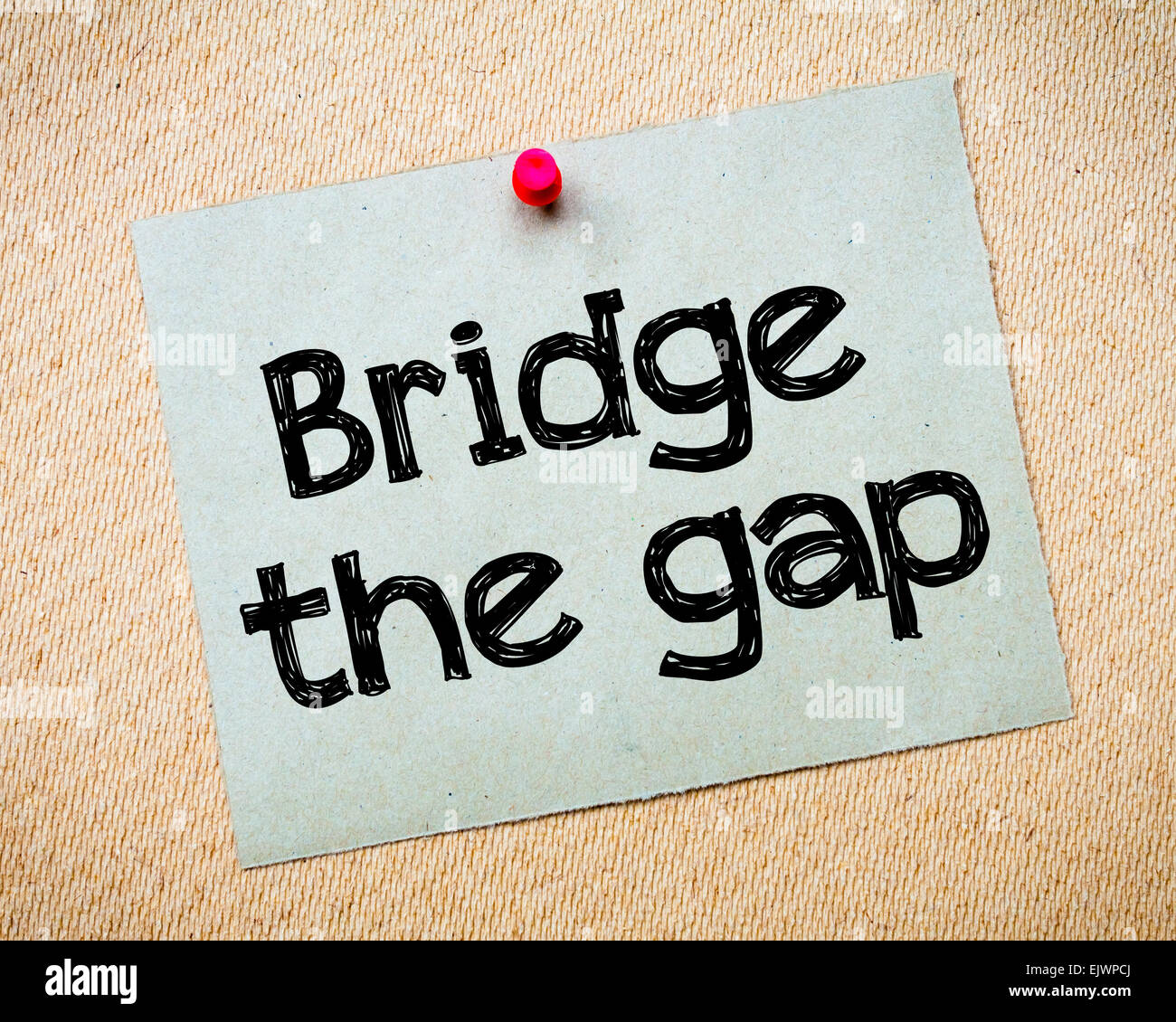 Bridge the gap Message. Recycled paper note pinned on cork board ...