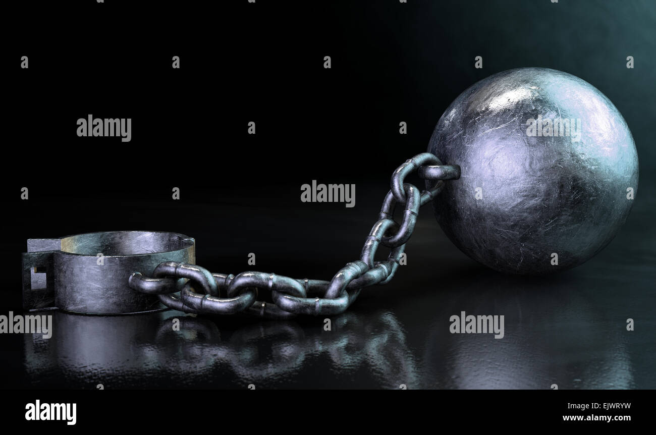 A vintage ball and chain with an open shackle on a dark backlit studio ...