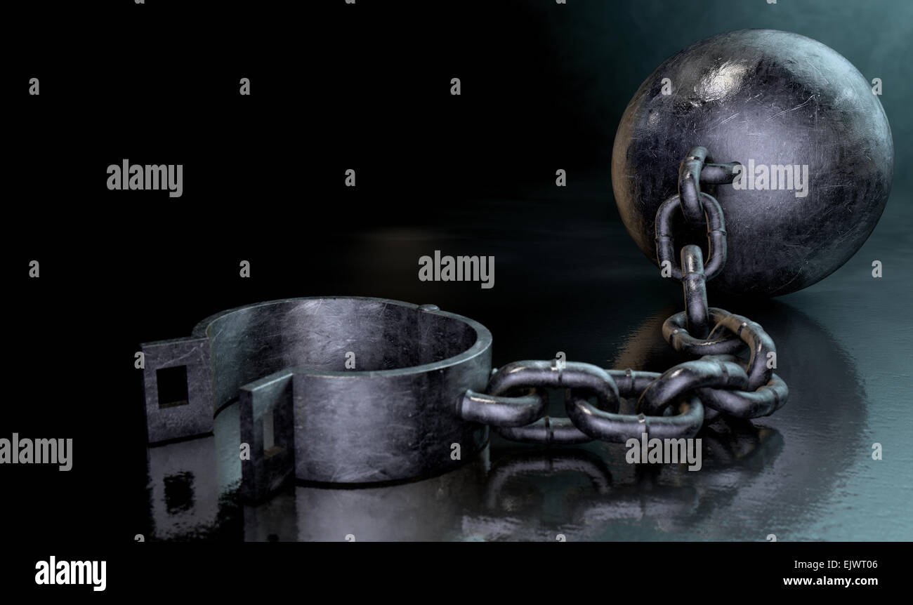 A vintage ball and chain with an open shackle on a dark backlit studio ...