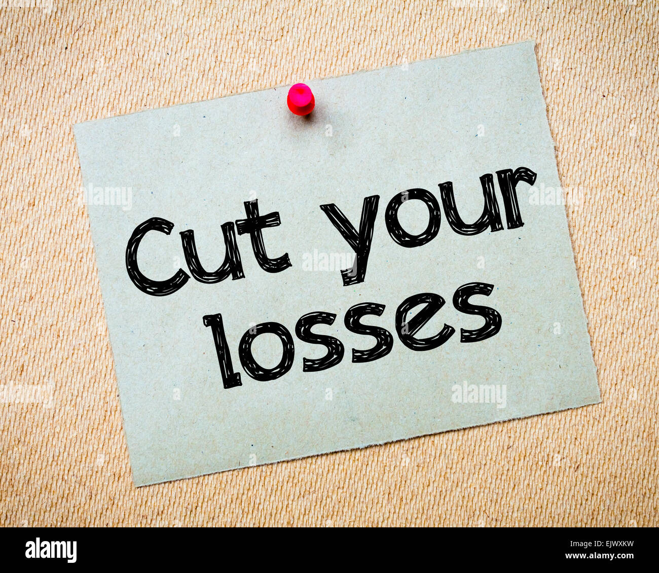 Cut your losses Message. Recycled paper note pinned on cork board ...