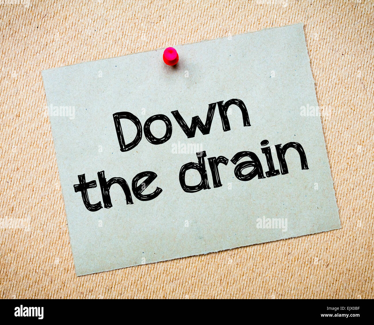 Down the drain Message. Recycled paper note pinned on cork board ...