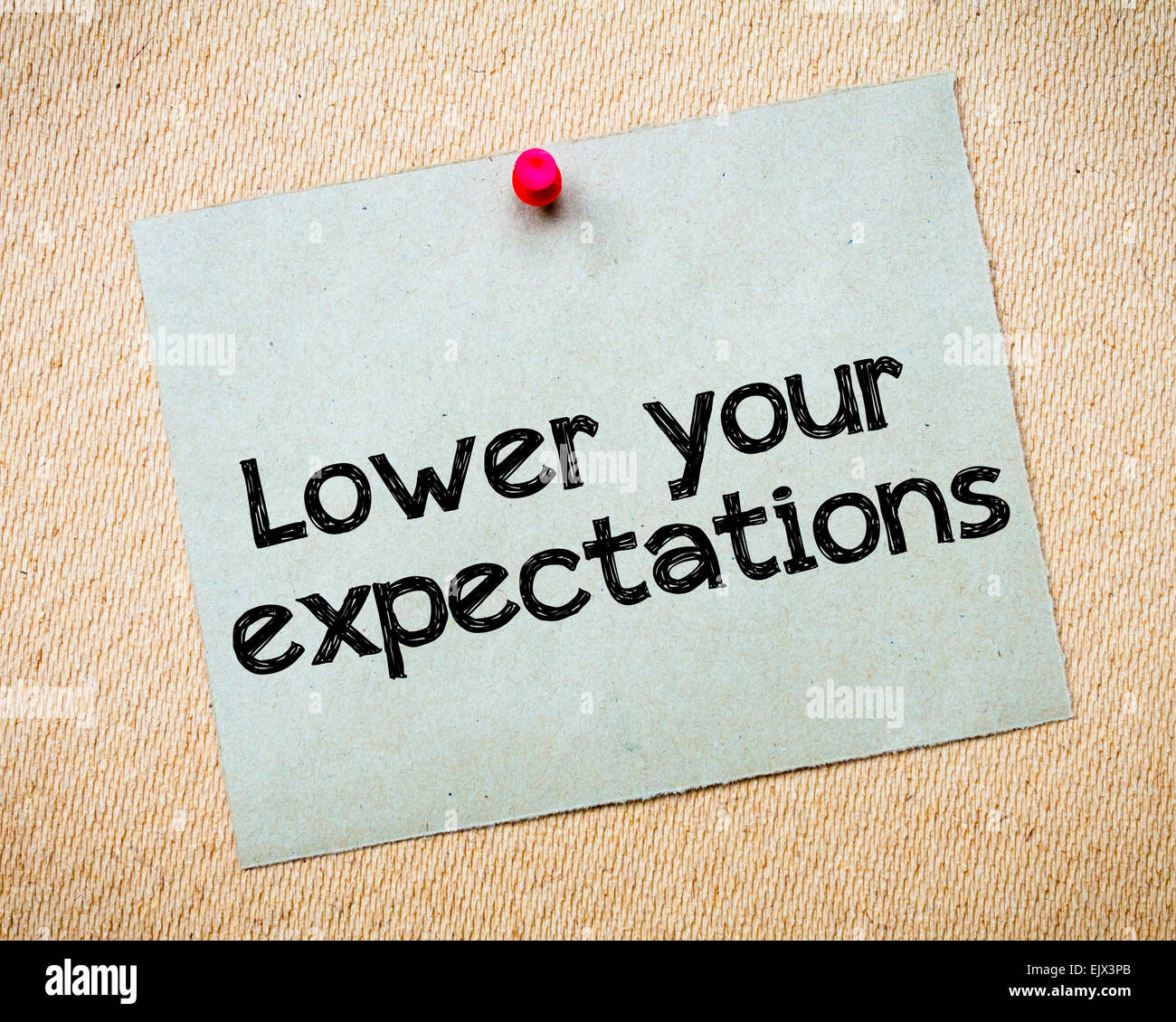 Lower your expectations Message. Recycled paper note pinned on cork ...
