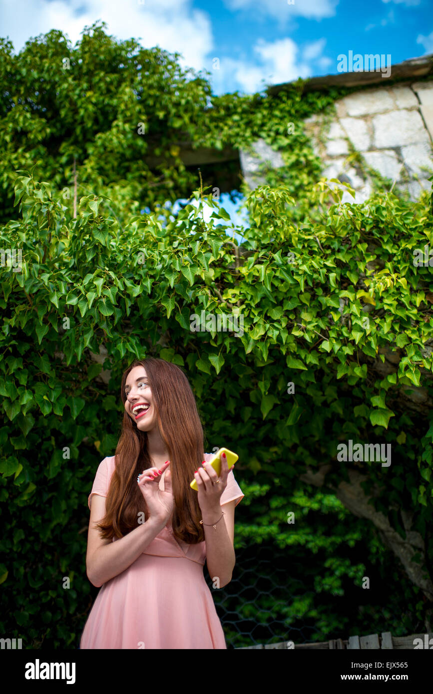 Woman using phone on green ivy background Stock Photo - Alamy