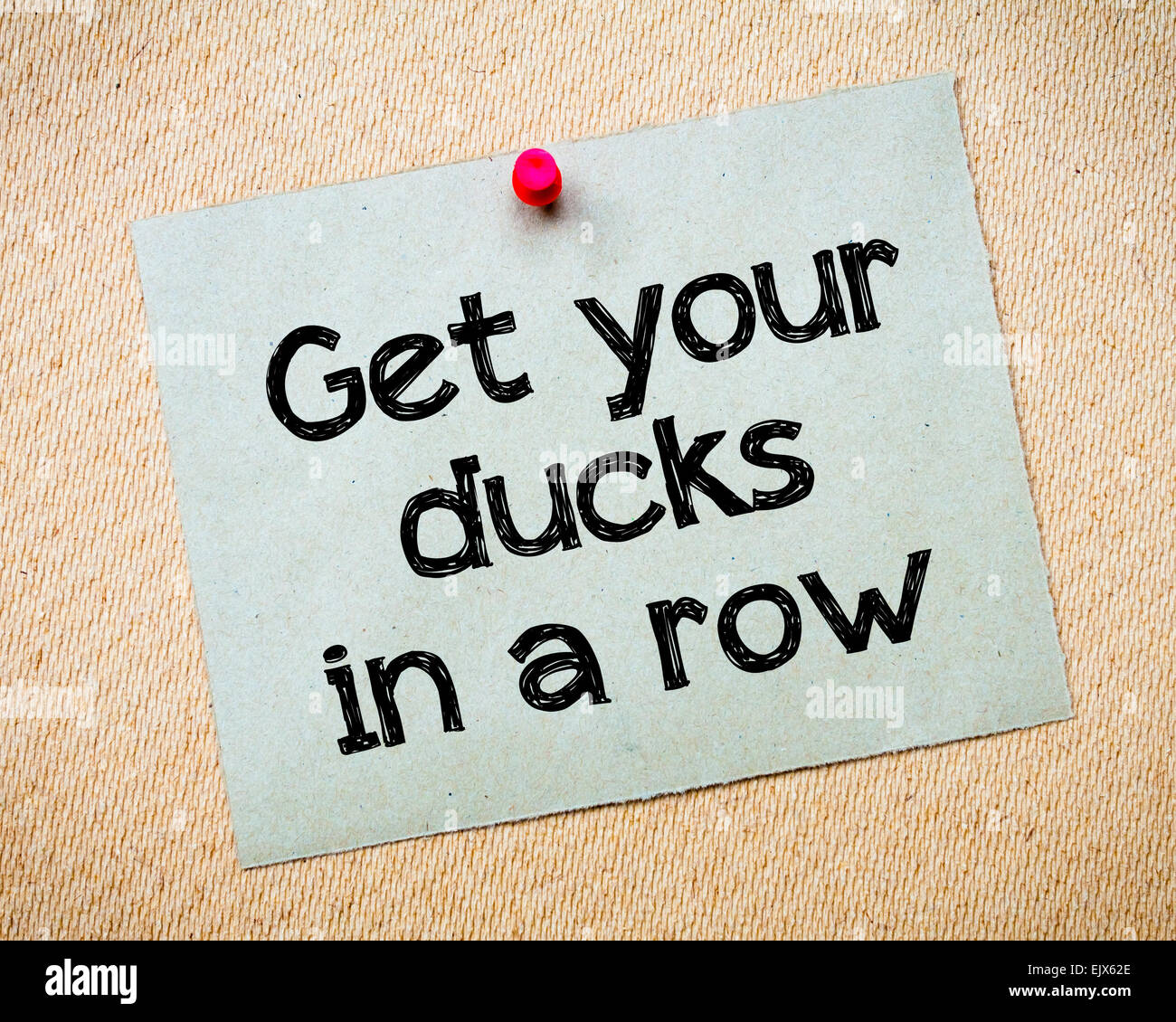 Get your ducks in a row Message. Recycled paper note pinned on cork ...