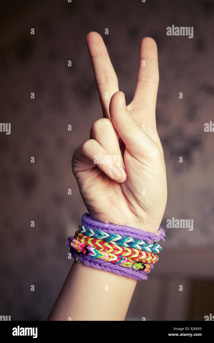 Child hand showing victory sign with colorful rubber rainbow loom ...