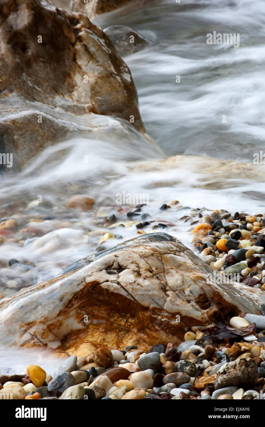 Motion blurred waves rolling on pebble beach Stock Photo - Alamy