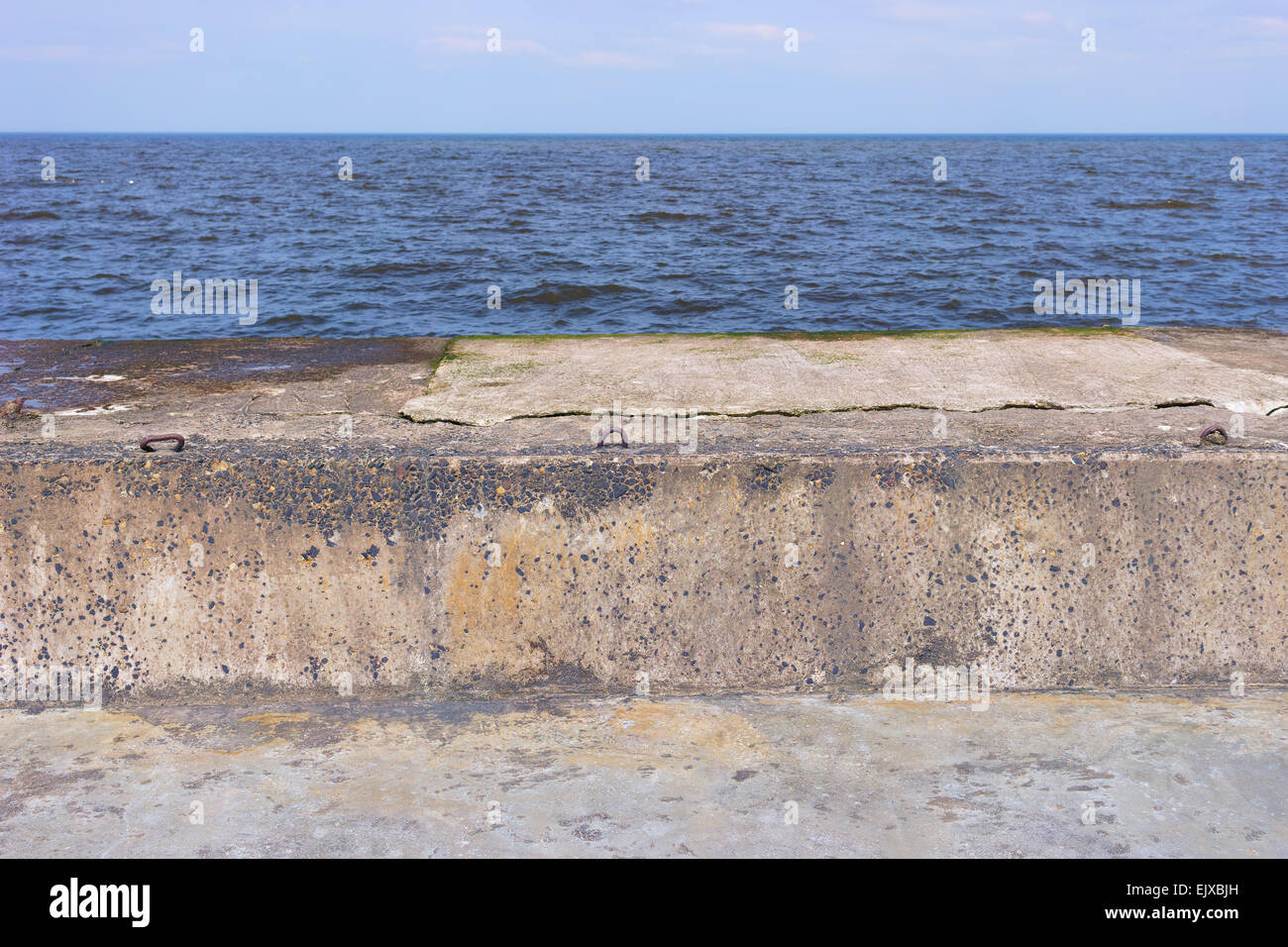 Concrete pier at the sea divides the landscape with the sea into equal ...