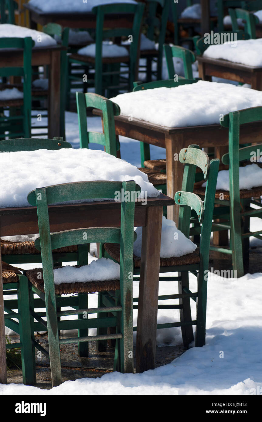 Snow covered tables and chairs in Greek taverna Stock Photo - Alamy