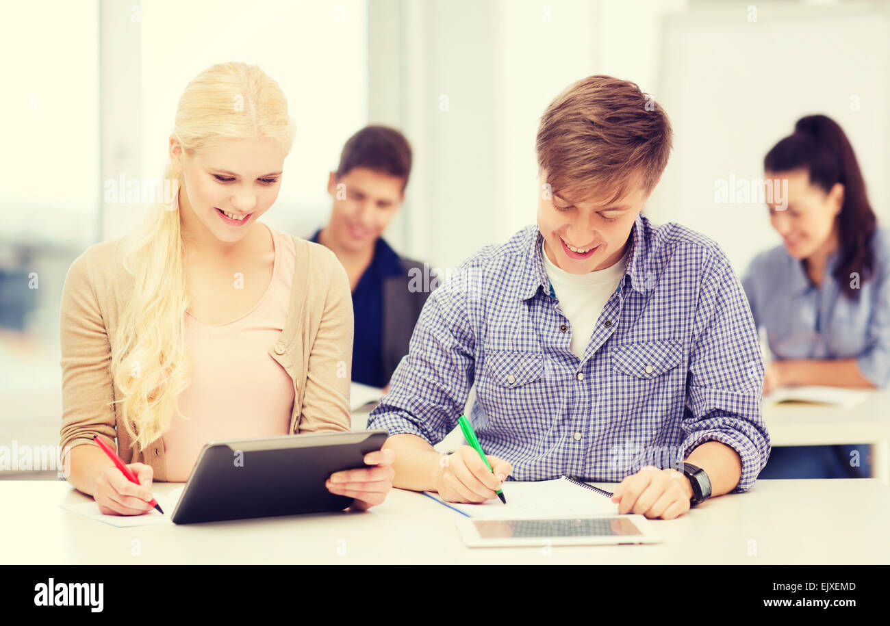 two smiling students with tablet pc and notebooks Stock Photo - Alamy