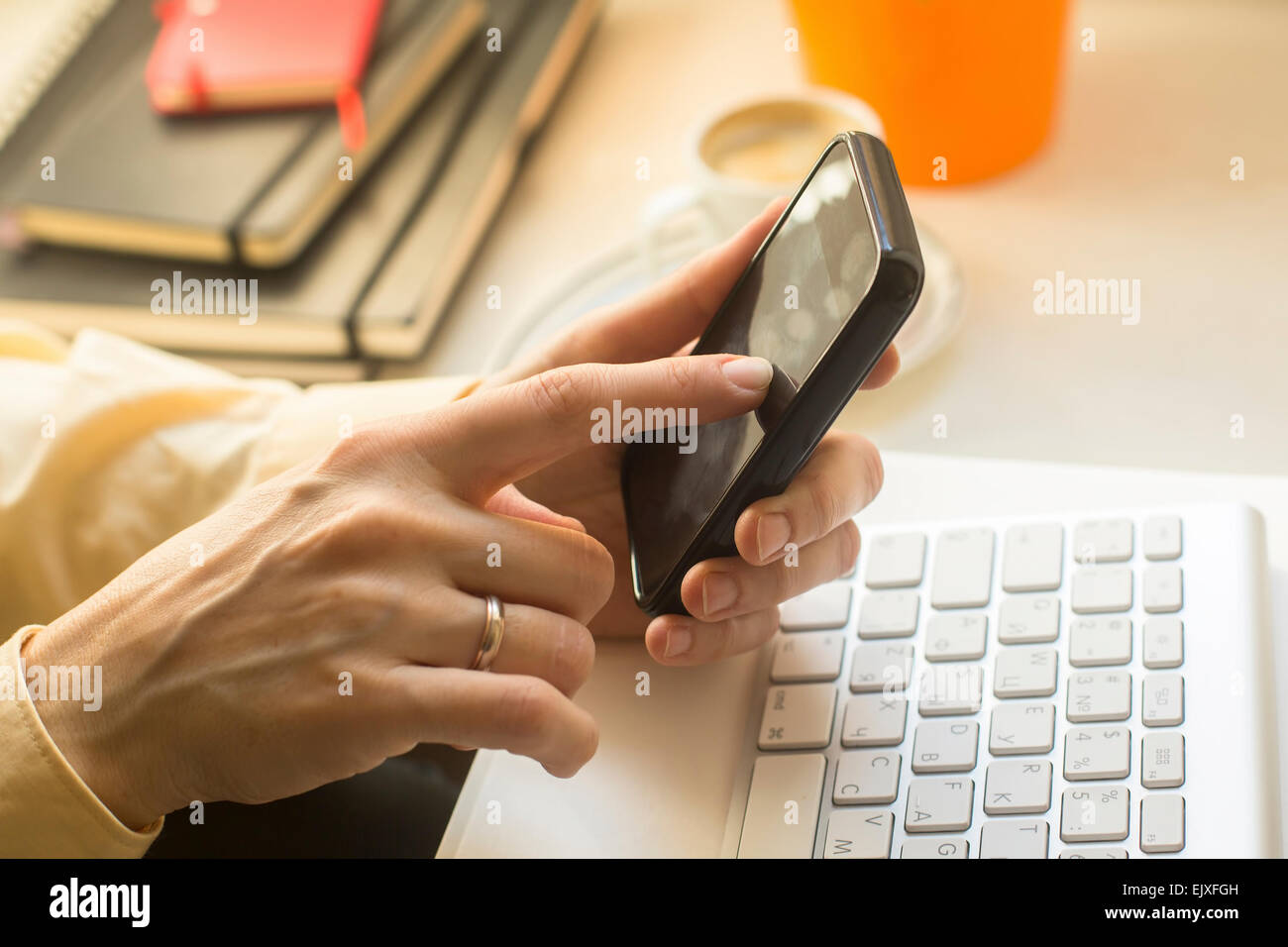 Fingers touched smartphone, keyboard in the background Stock Photo - Alamy