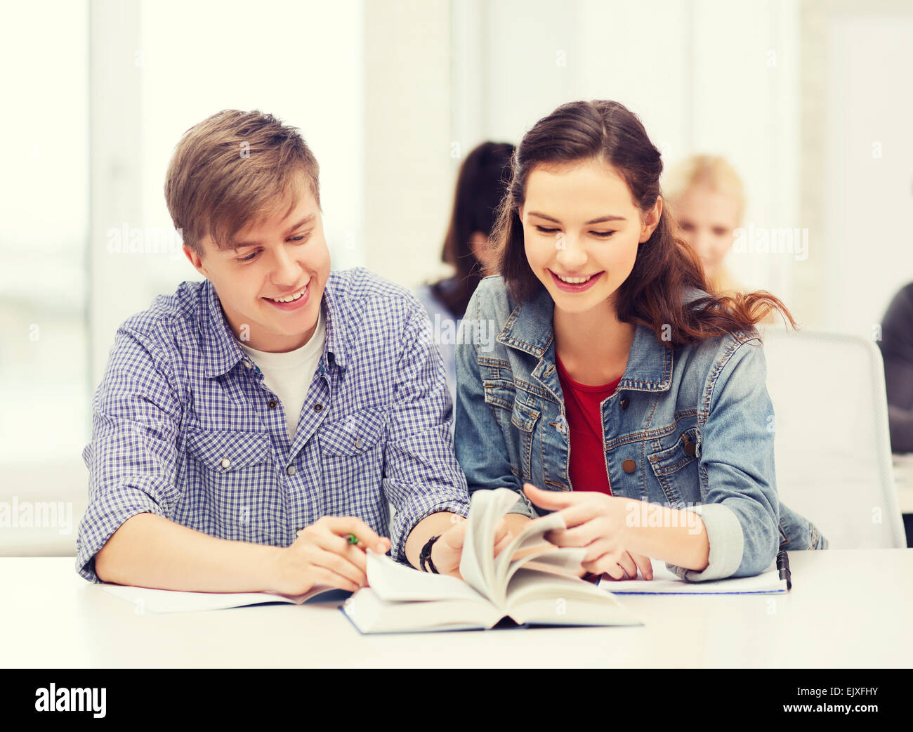 two teenagers with notebooks and book at school Stock Photo - Alamy