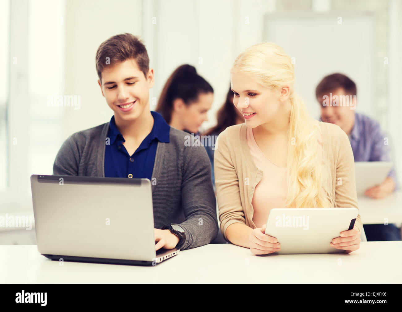 two smiling students with laptop and tablet pc Stock Photo - Alamy