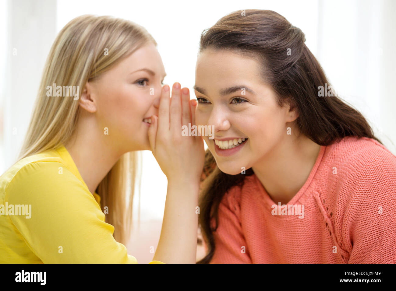 one girl telling another secret Stock Photo - Alamy