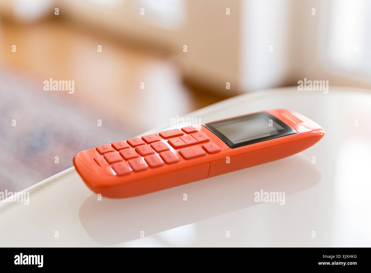 Orange telephone on glass table Stock Photo - Alamy